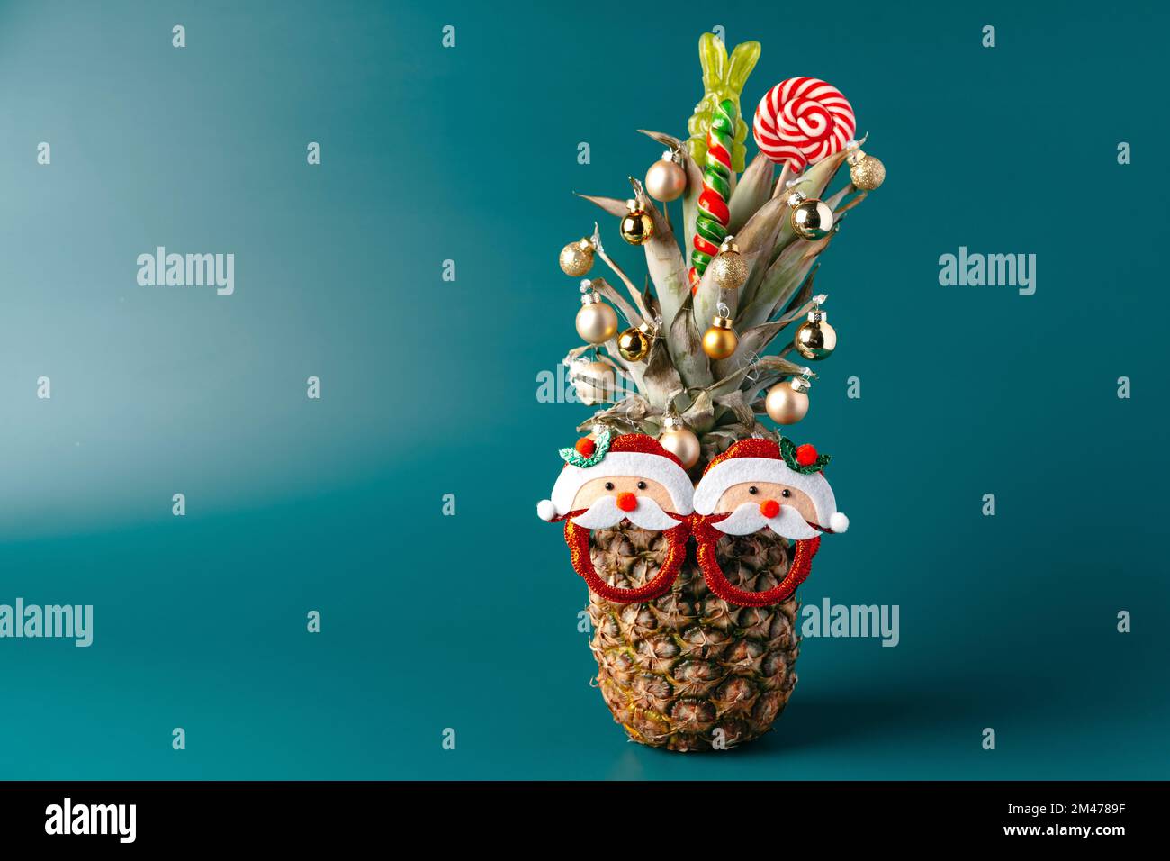 Creative pineapple with Christmas decorations on studio background ...