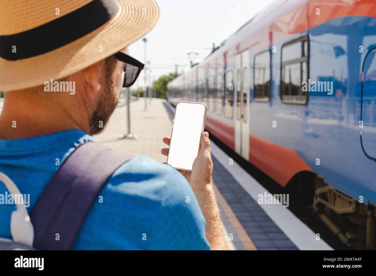 Man in hat holding his smartphone and checking train schedule mobile ...