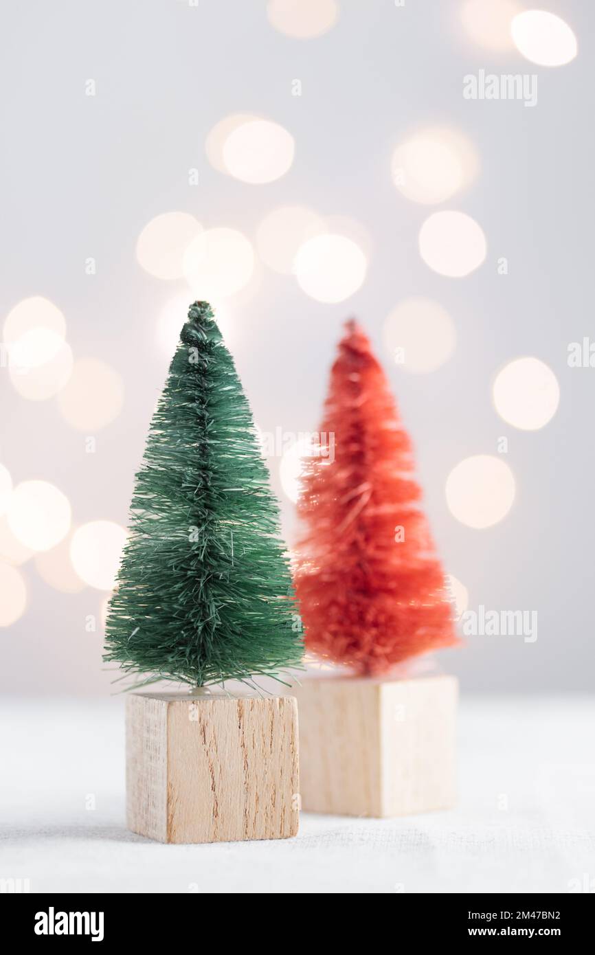 Two cute Christmas miniature fir trees on a white table with bokeh ...