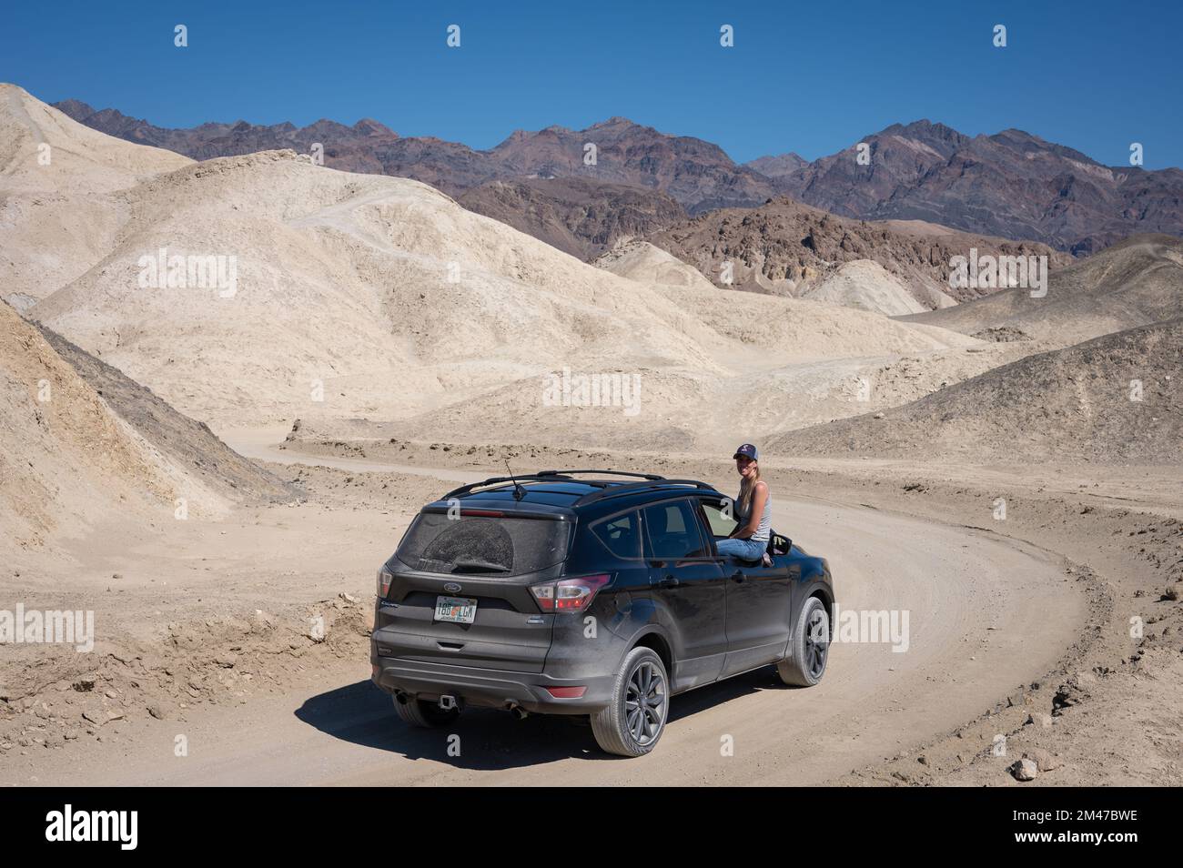young girl driving a black Ford Escape SUV through the desert of Death ...