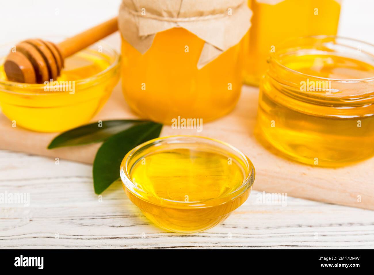 Honey in jar with leaves and honey dipper on colored background top ...