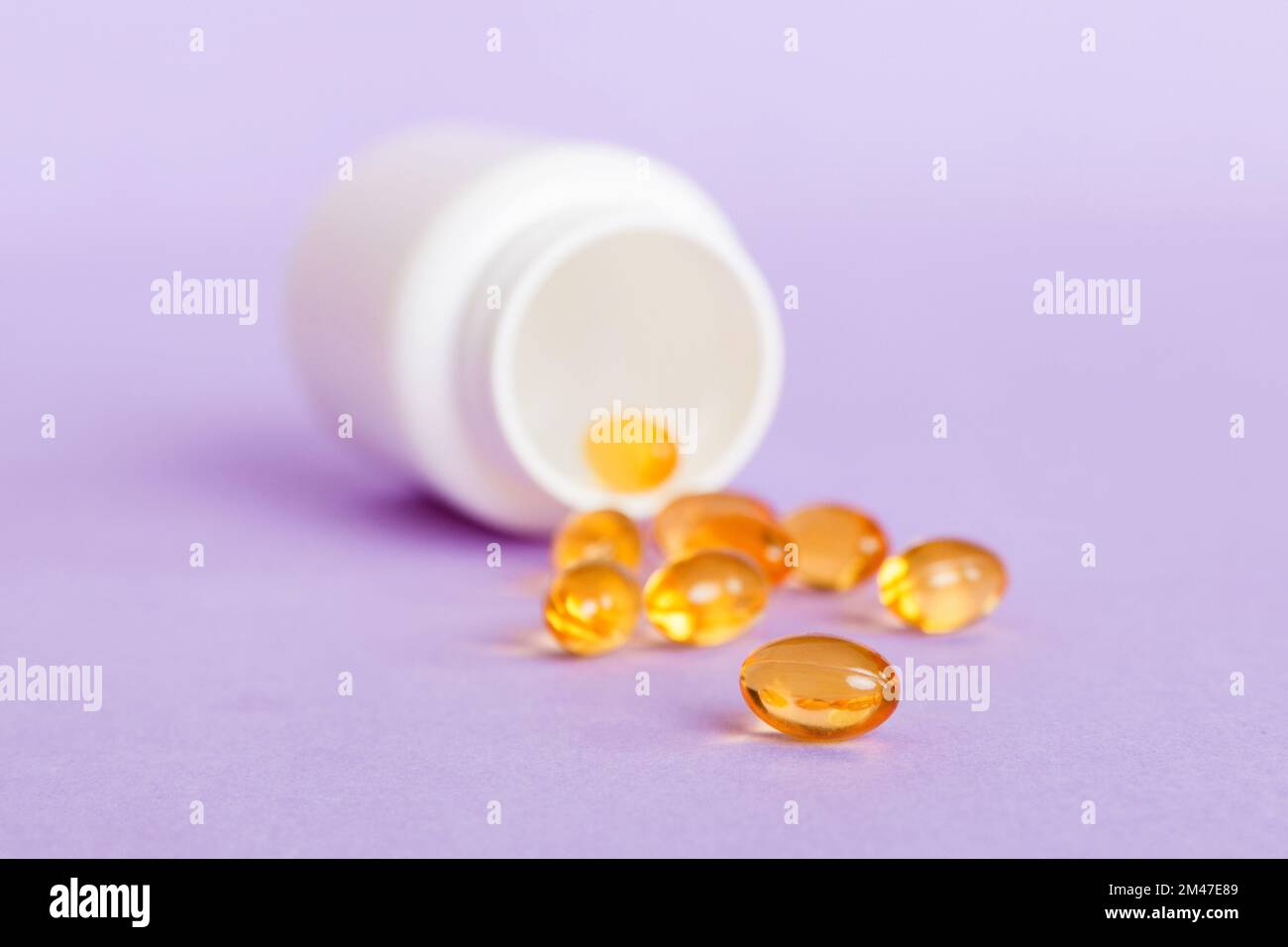 Soft gels pills with Omega-3 oil spilling out of pill bottle close-up ...