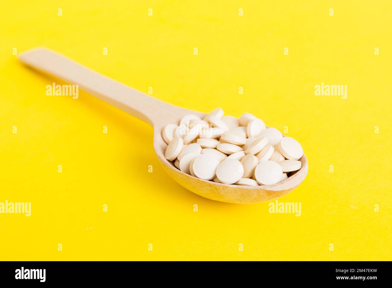 Heap of white pills on colored background. Tablets scattered on a table ...