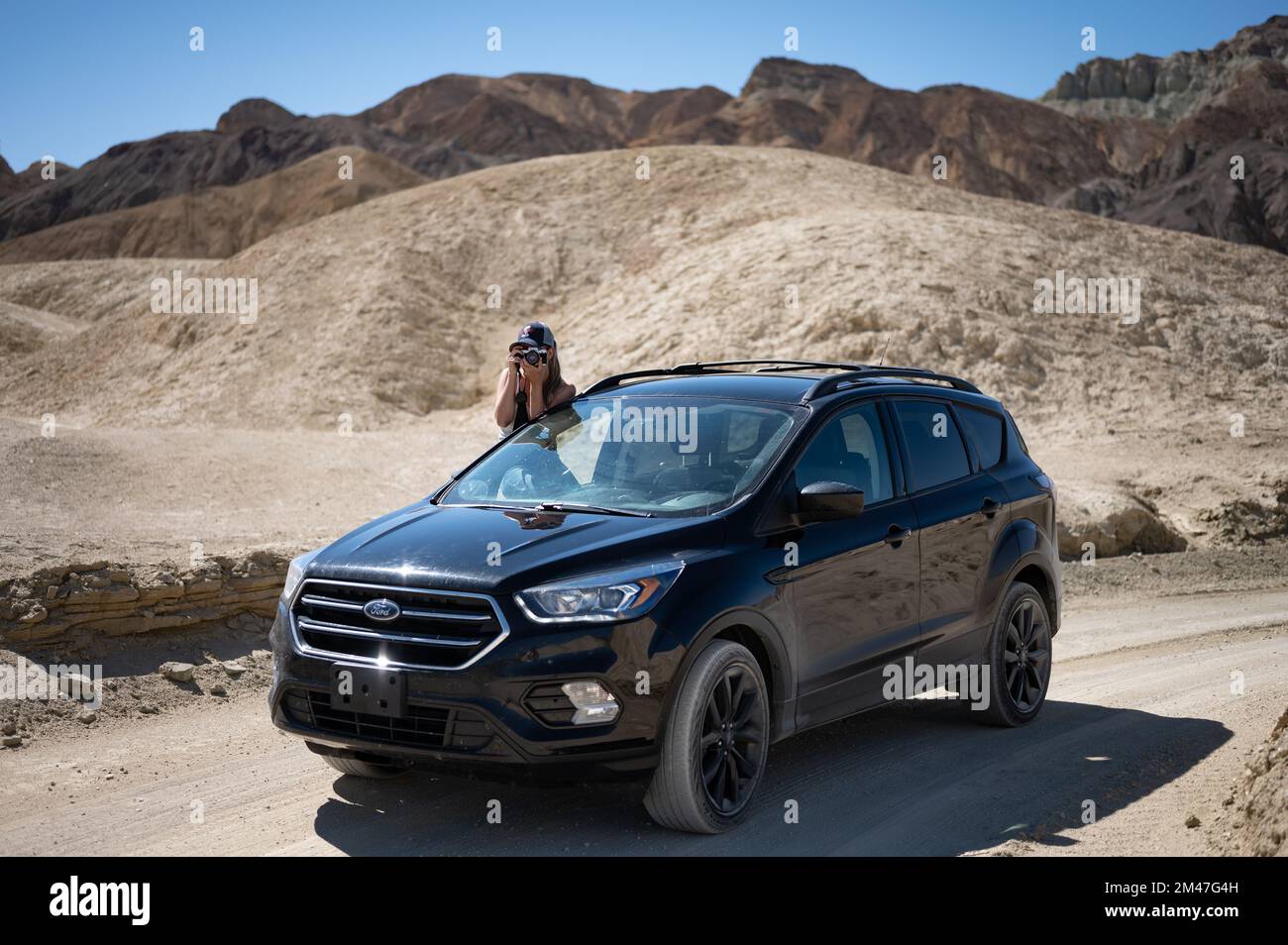 Adventurous young girl driving a black Ford Escape SUV through the ...