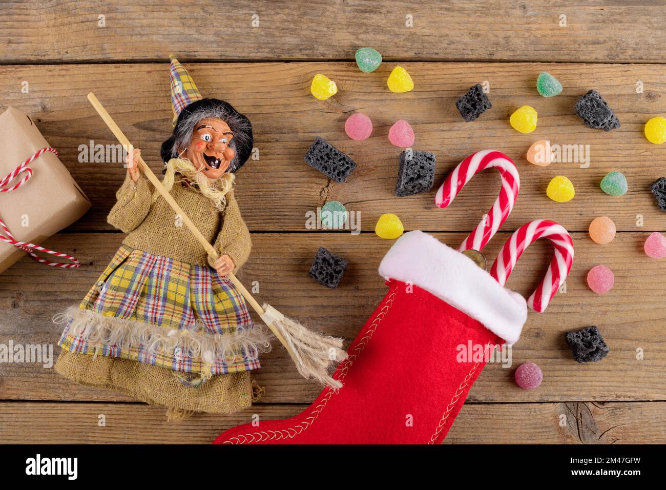 The witch Befana and red stocking with sweet coal and candy on rustic ...