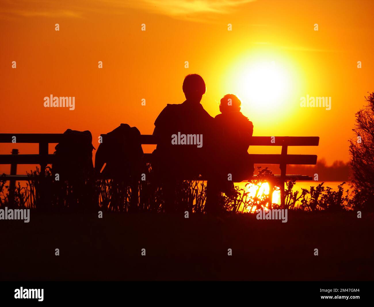 couple sitting bench sunset relaxing Stock Photo - Alamy