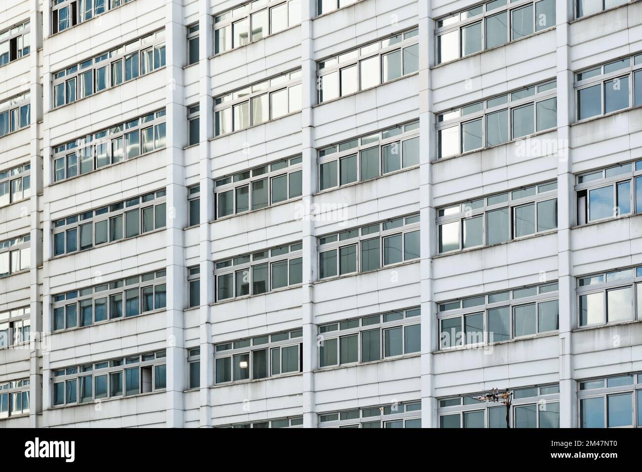 An outdoor shot of the exterior of a white building with many windows ...