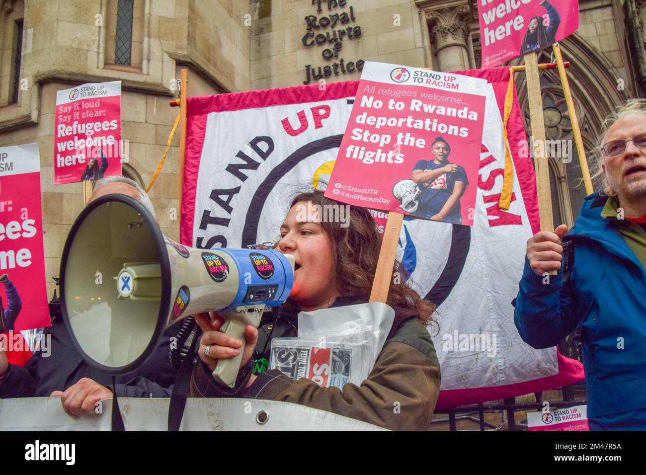 A protester holding a pro-refugee placard chants slogans through a ...
