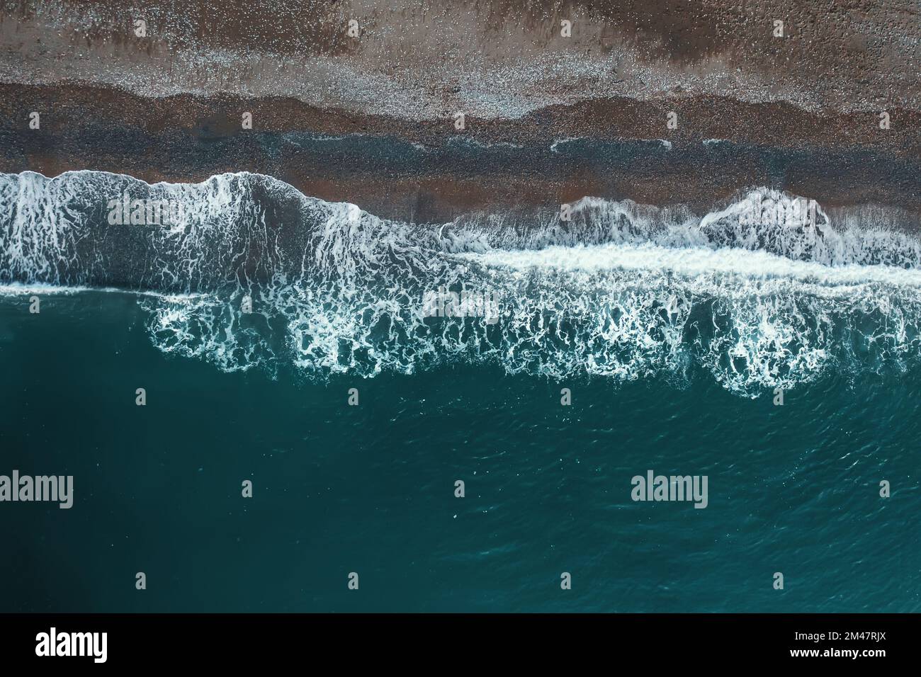 Aerial top view from drone of dark sand beach and sea or ocean water ...
