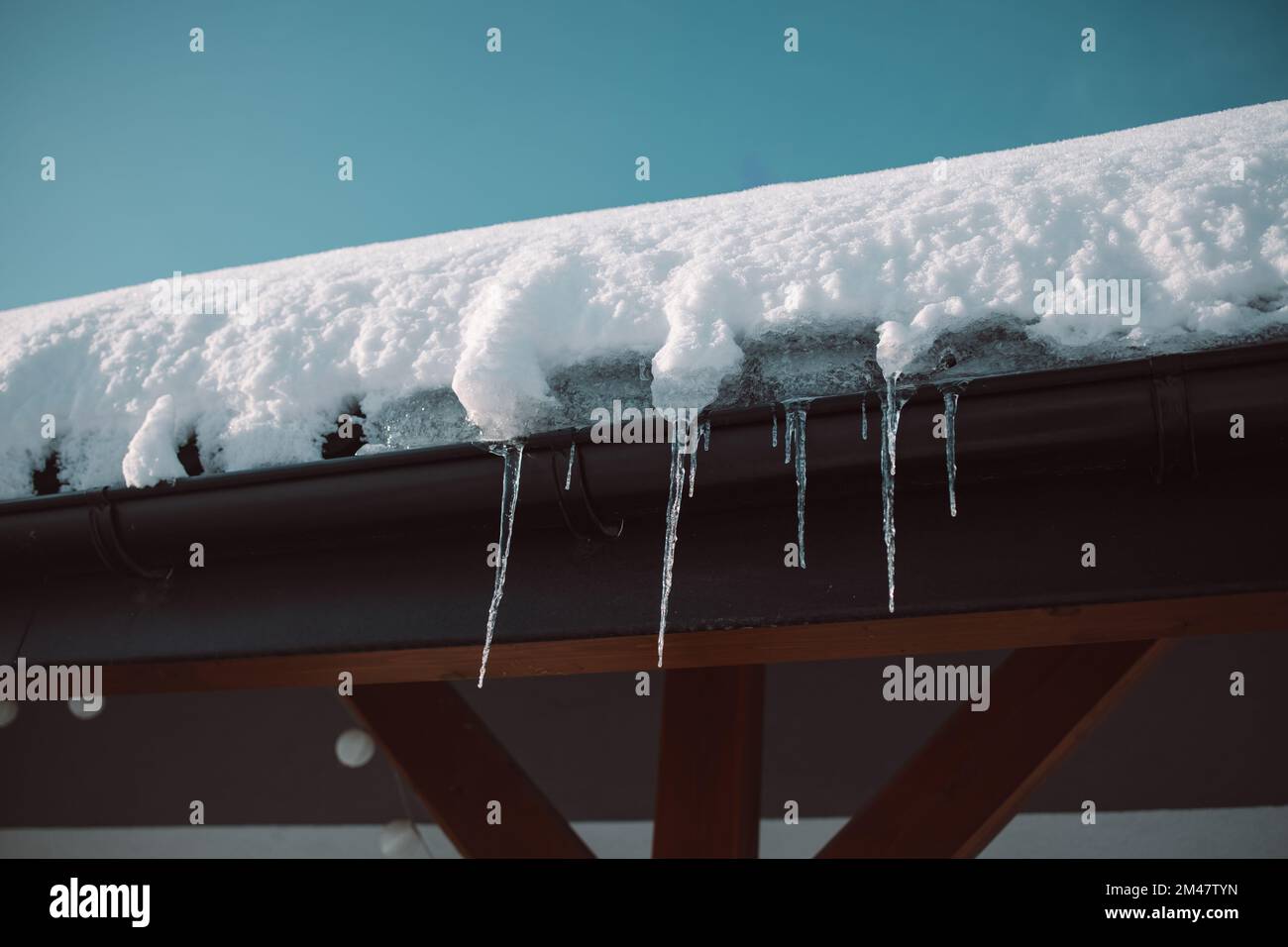 Sharp icicles and melted snow hanging from eaves of roof. Beautiful ...