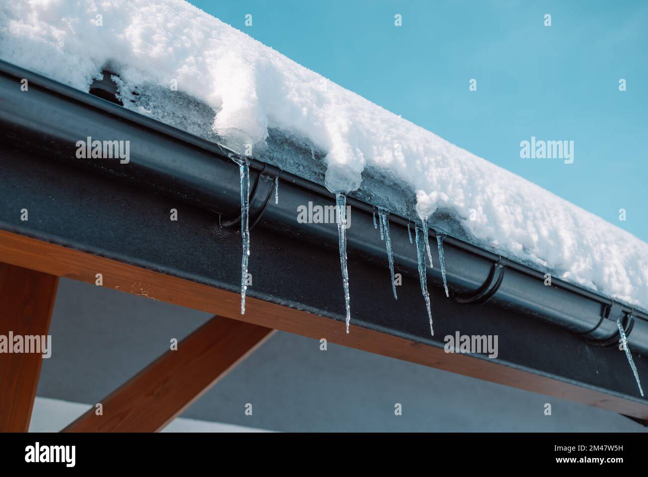 Sharp icicles and melted snow hanging from eaves of roof. Beautiful ...