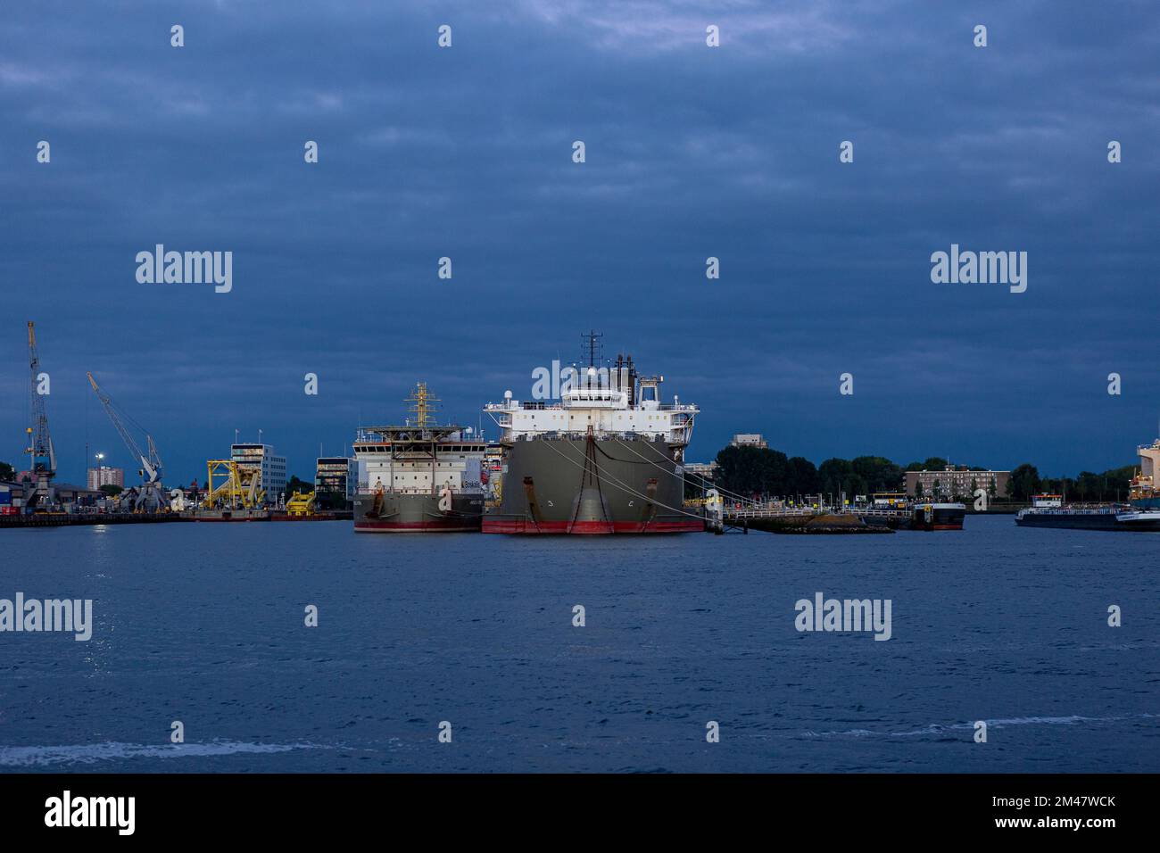 Industrial inland shipping colourful cranes in port at sunset blue hour ...