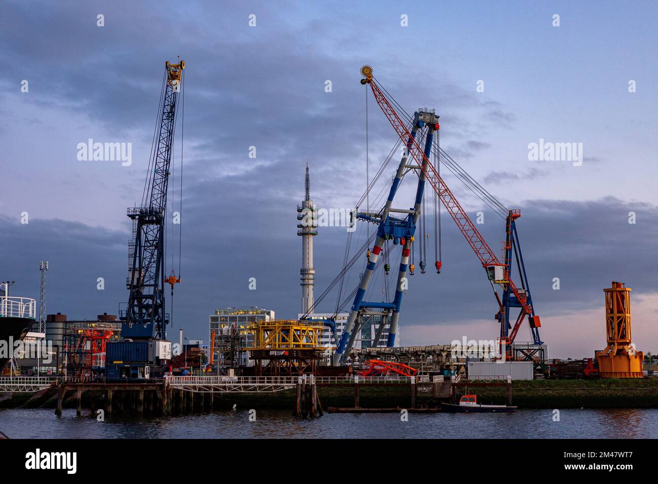 Industrial inland shipping colourful cranes in port at sunset blue hour ...