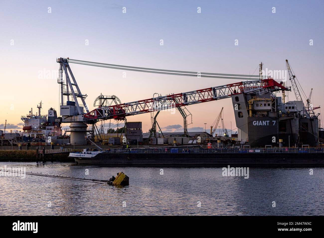 Industrial inland shipping colourful cranes in port at sunset blue hour ...