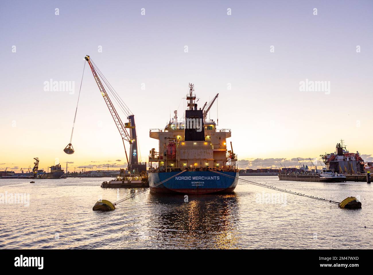 Industrial inland shipping colourful cranes in port at sunset blue hour ...