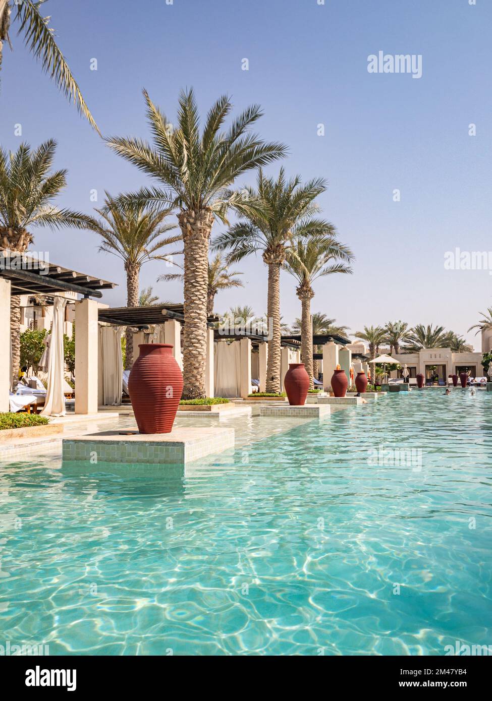 The vast infinity pool with palm trees and cabanas at the Al Wathba Desert Resort and Spa Stock ...