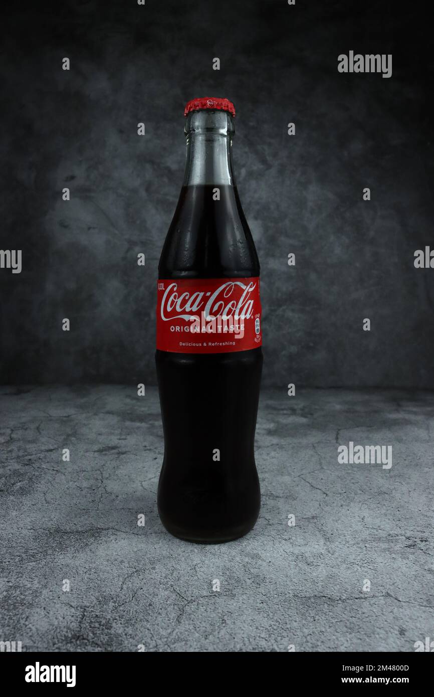 A vertical shot of Coca Cola bottle against modern dark stony ...