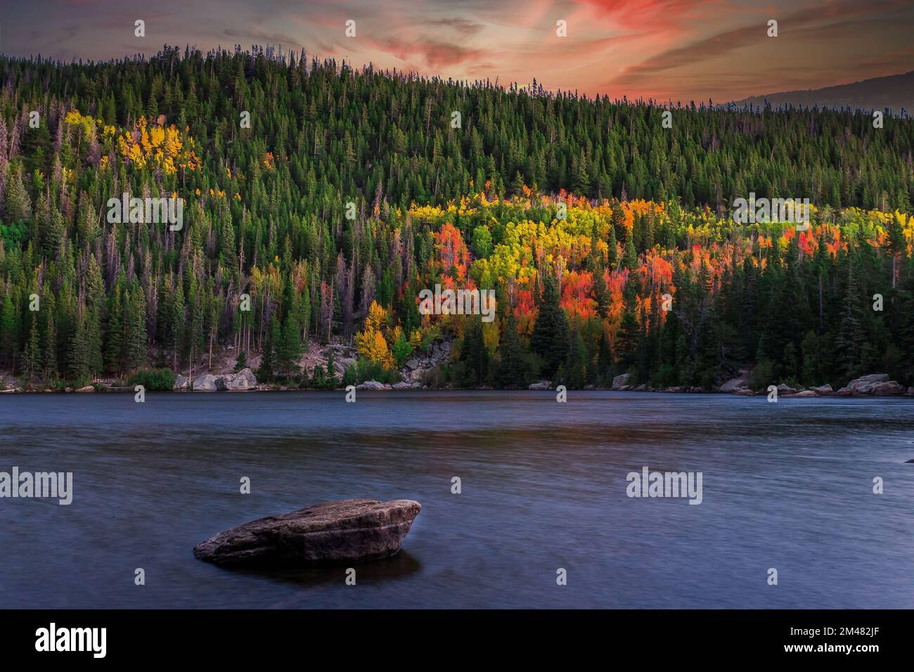 A golden red sunset over the lake with trees and mountain Stock Photo ...