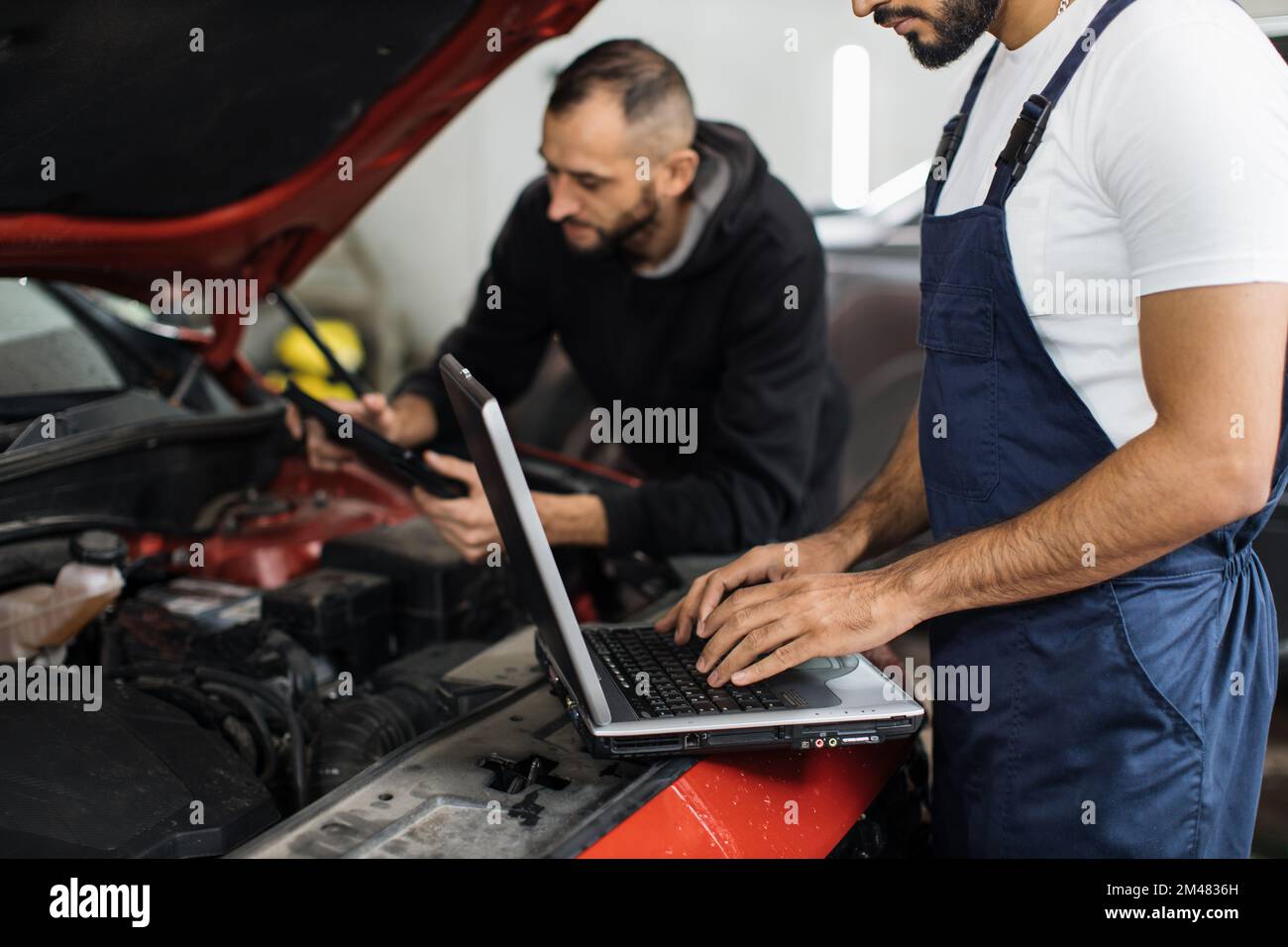 Cropped view of bearded men colleagues car technician mechanics ...