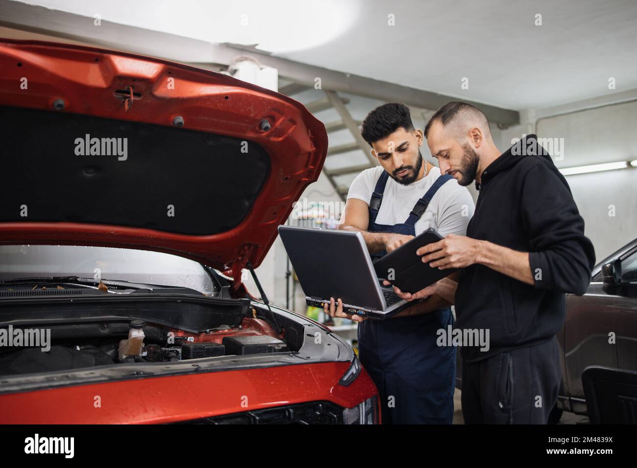 Car service station. Two young bearded attractive mechanics men ...