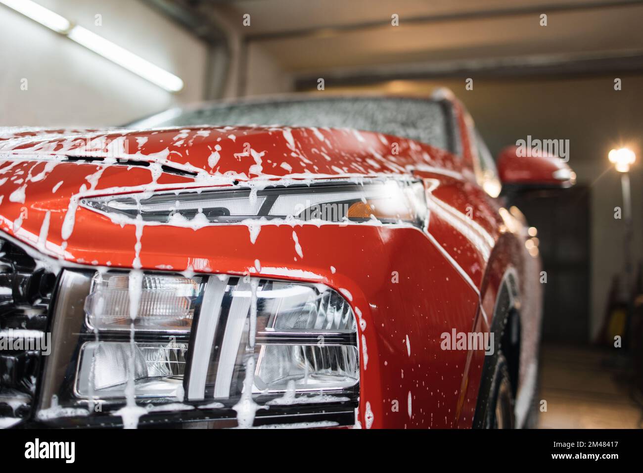 Washing a car headlight at auto wash service. Soapy red car. Washing of ...