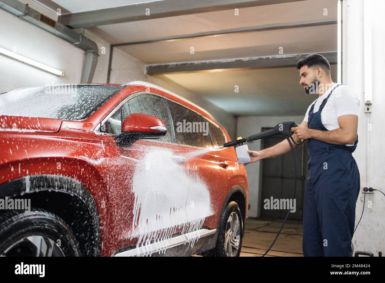 Side view portrait of young pleasant car wash worker, wearing ...