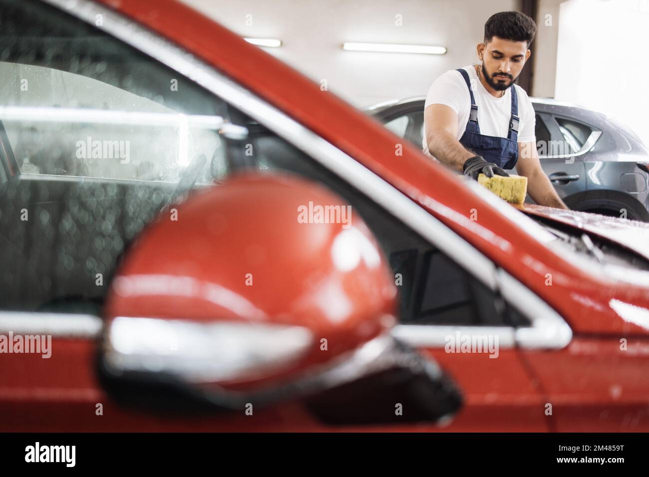 Car wash and clean with shampoo and sponge. Young concentrated bearded ...