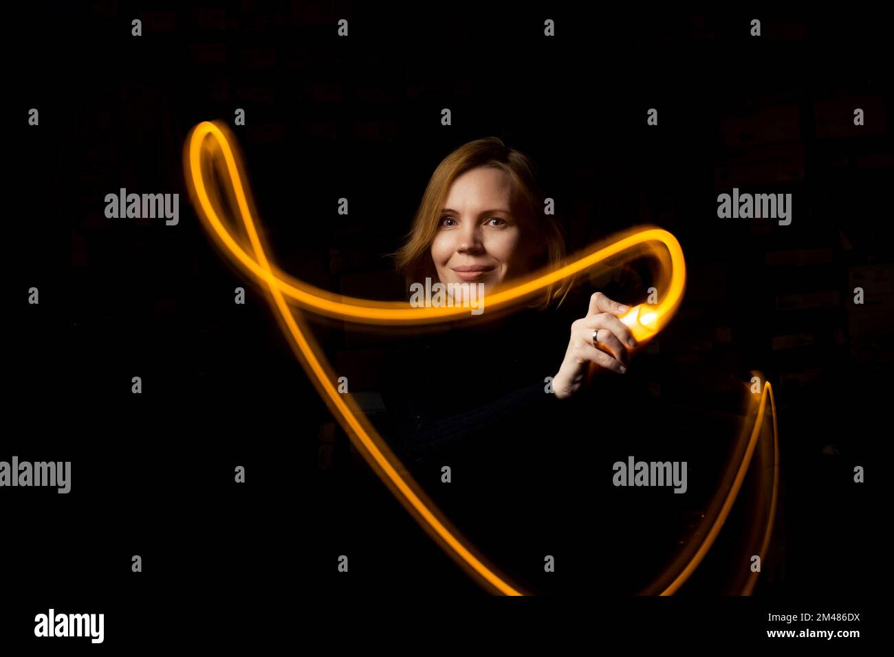 Write with light at long exposure in the dark. A middle-aged woman ...
