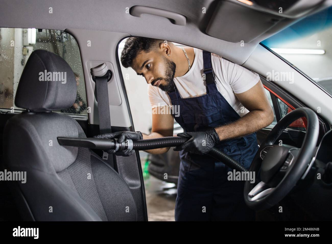 Car wash and detailing service. Bearded male worker in overalls and ...