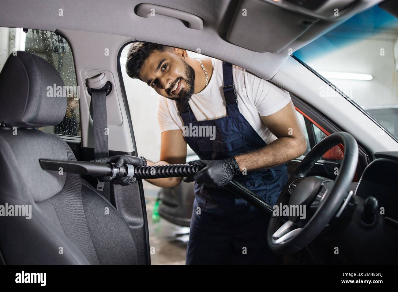 Car wash and detailing service. Bearded male worker in overalls and ...