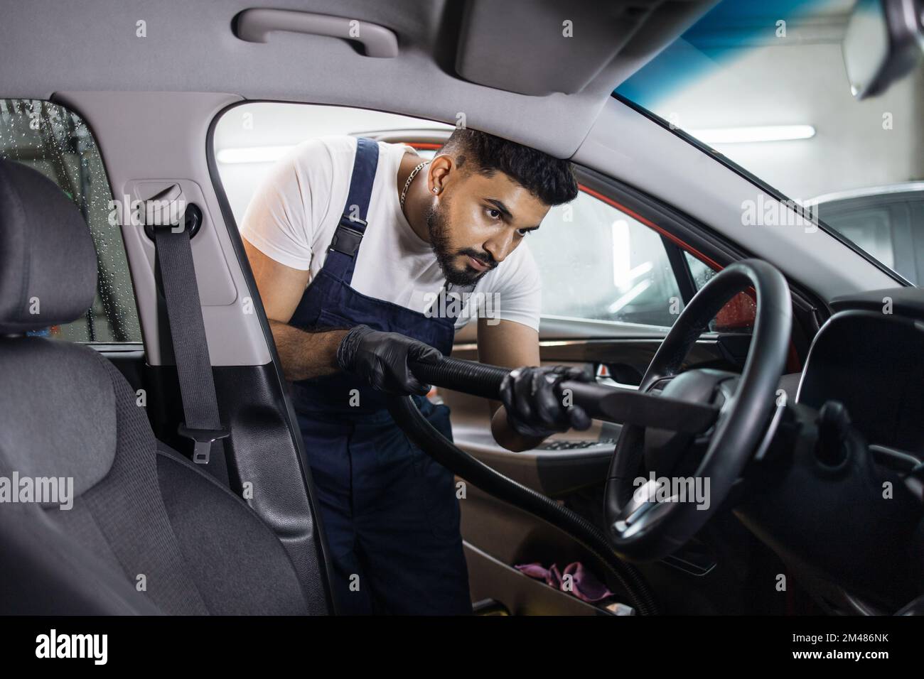 Car wash and detailing service. Bearded male worker in overalls and ...