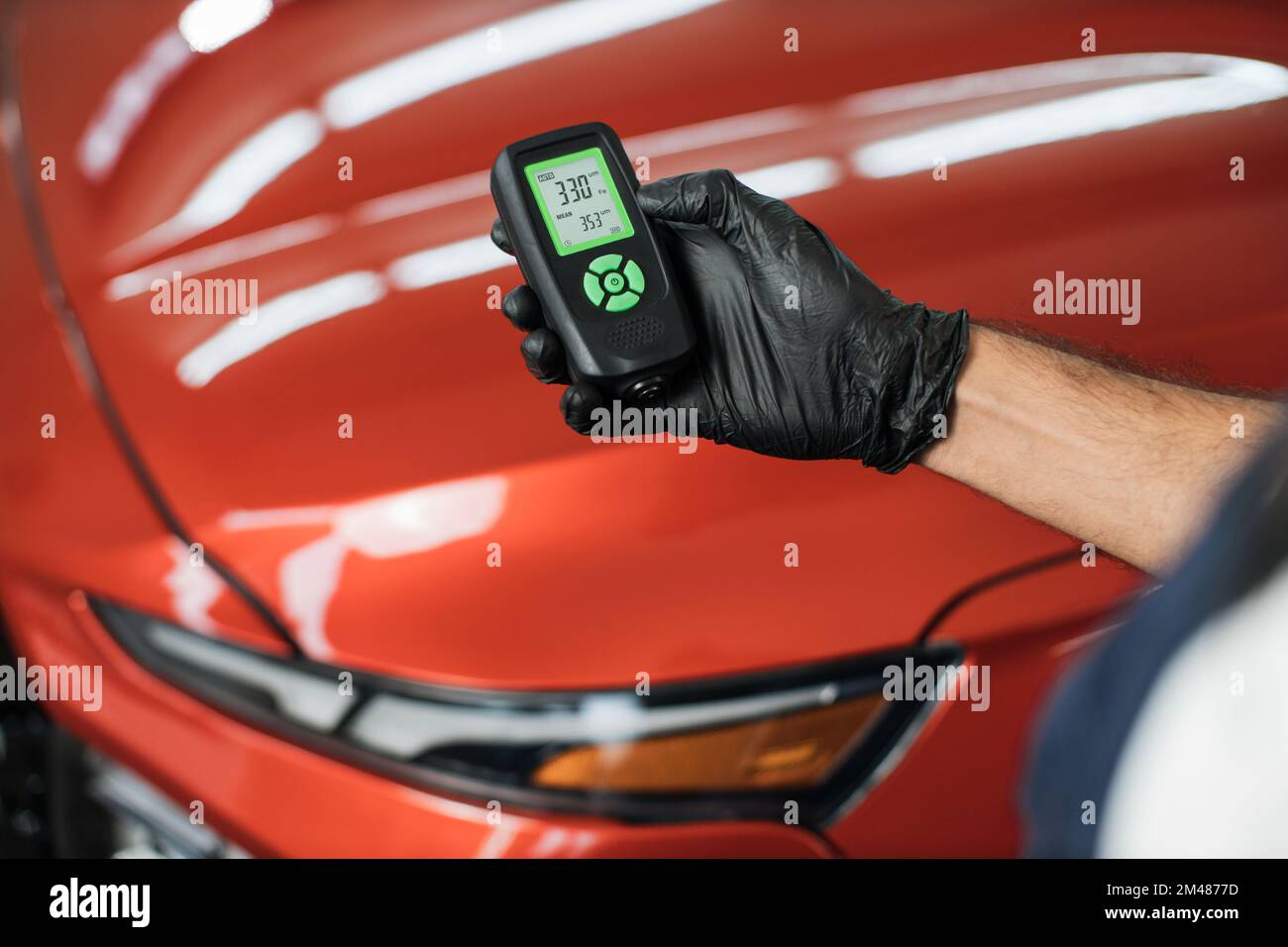 Closeup view of male hand, using film coating thickness gauge device to ...