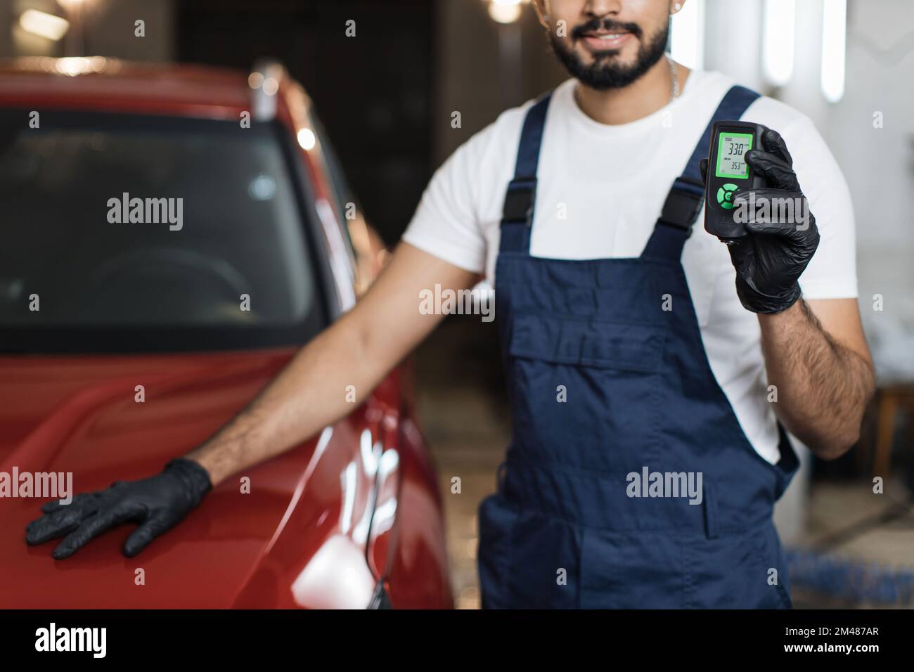 Cropped view of bearded young male inspector measuring paint cover ...