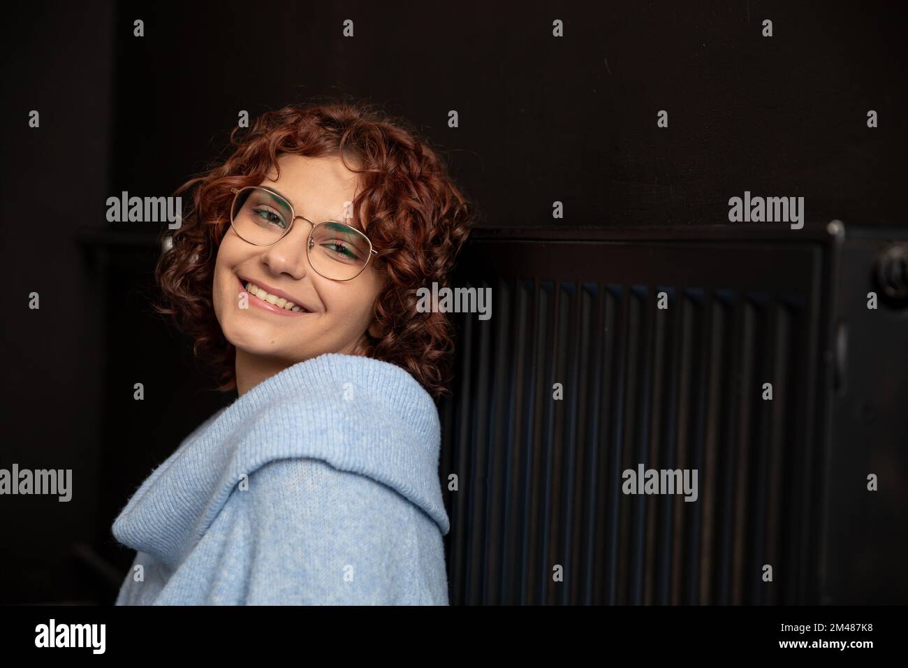 A smiling girl sits and leans against a hot radiator Stock Photo - Alamy