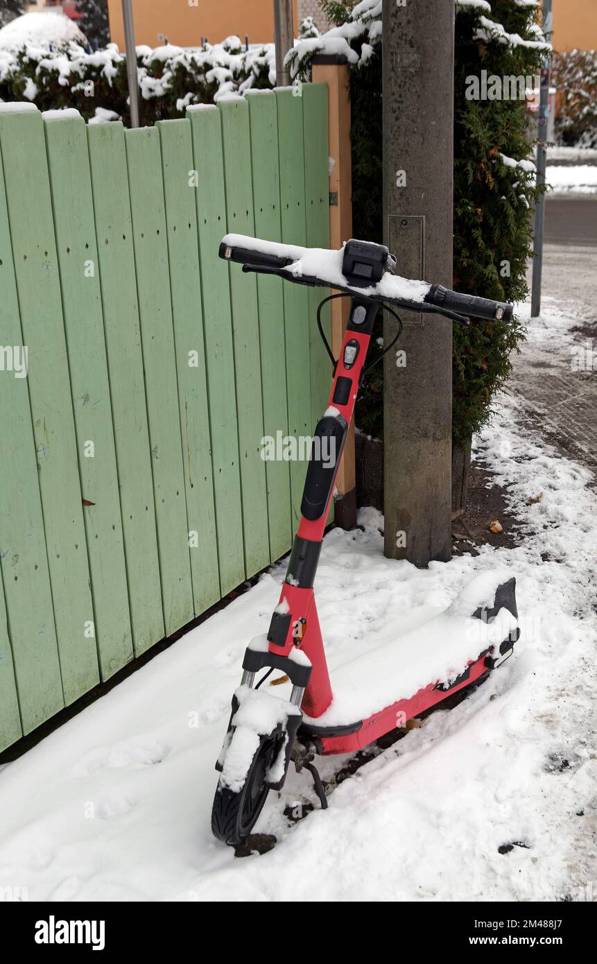 Winter, cold: snow covered e-scooter in front of a board fence Stock ...