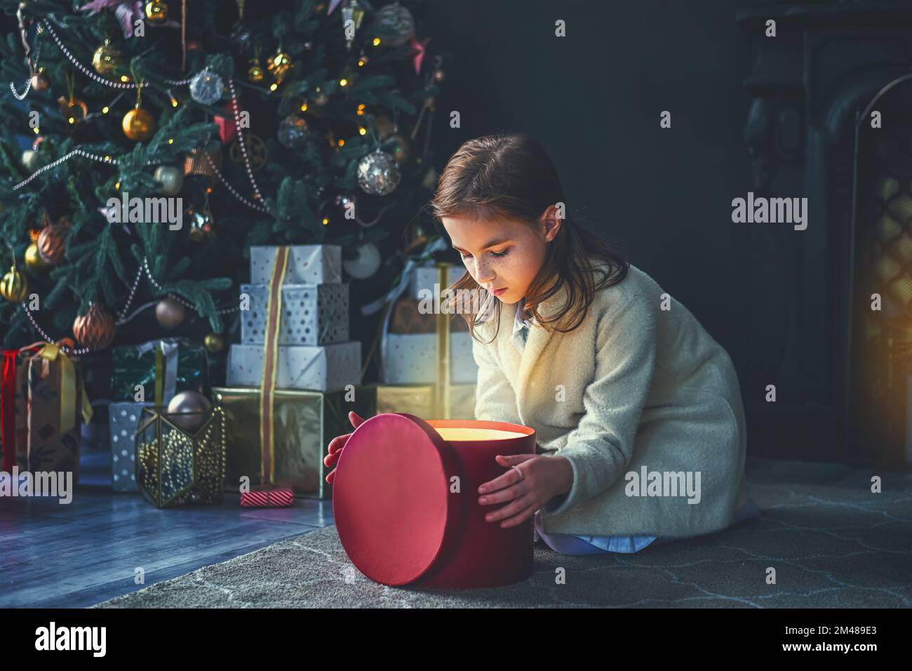 Cute girl opening Present next to Cristmas Tree. Happy Girl looking ...