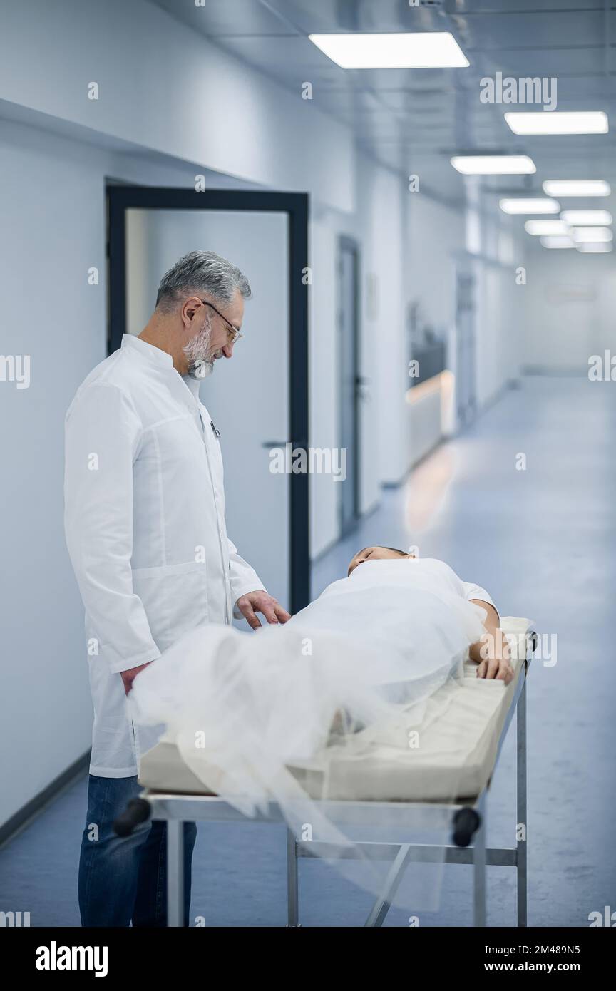 A mature doctor carrying the gurney with a patient Stock Photo - Alamy