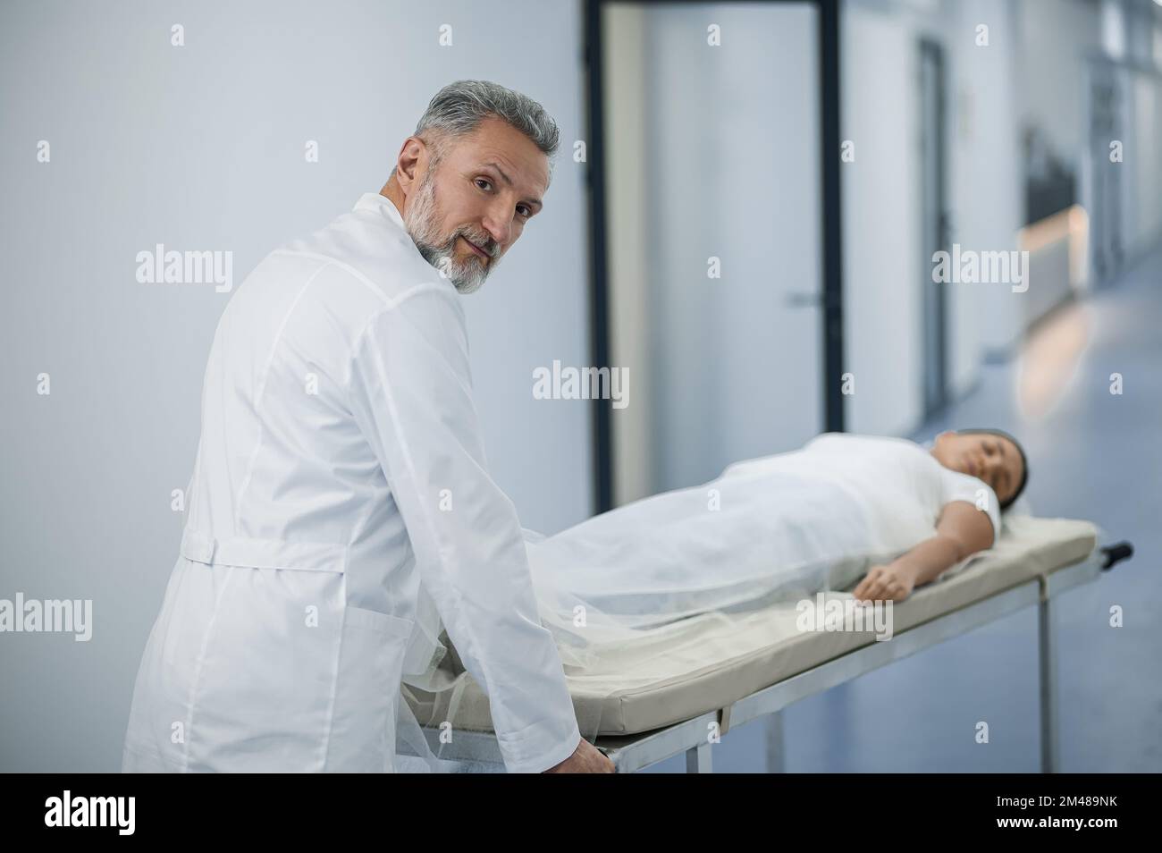 A mature doctor carrying the gurney with a patient Stock Photo - Alamy