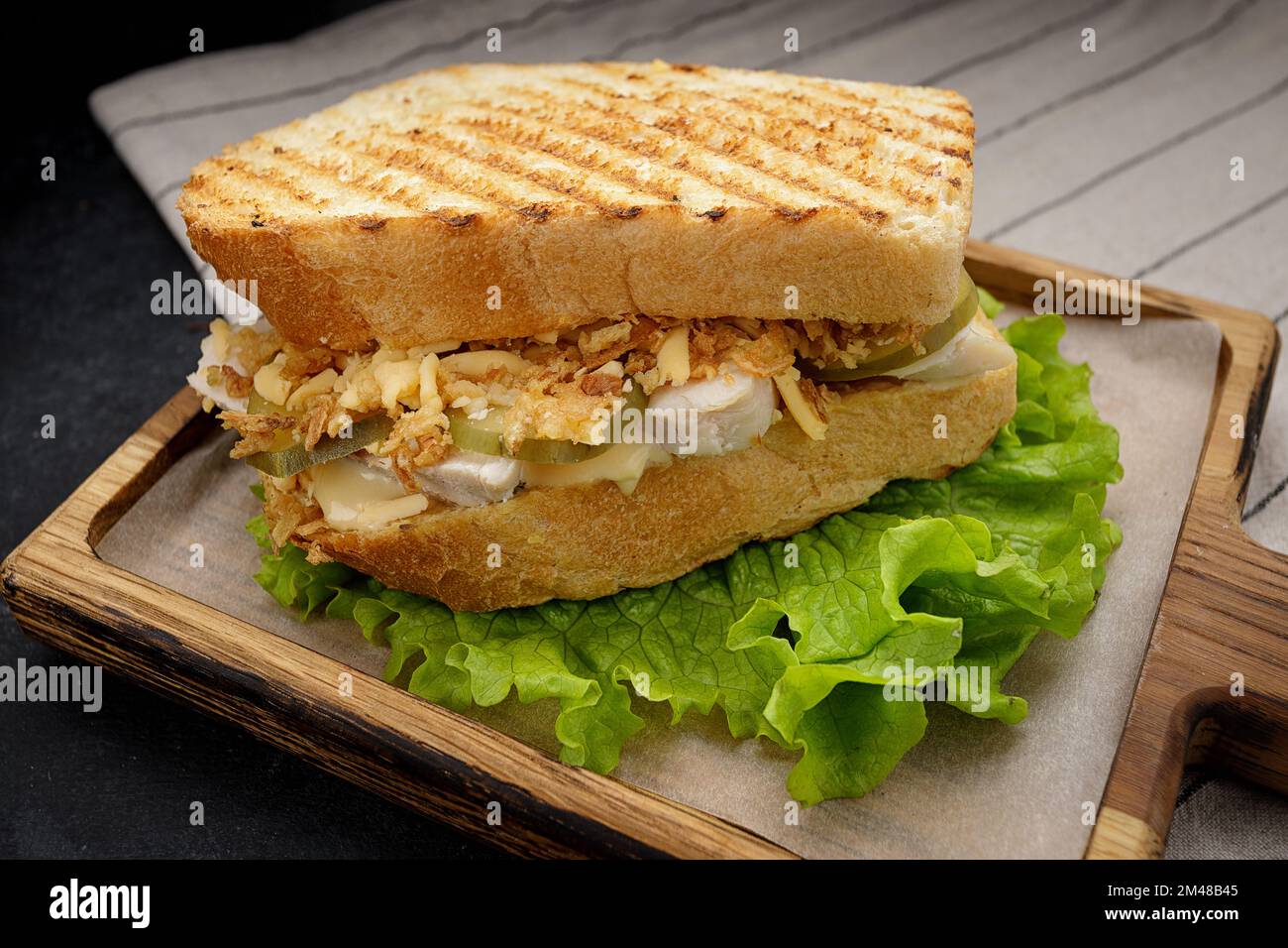 Sandwich with meat, cheese and cucumber on a wooden board, close-up ...