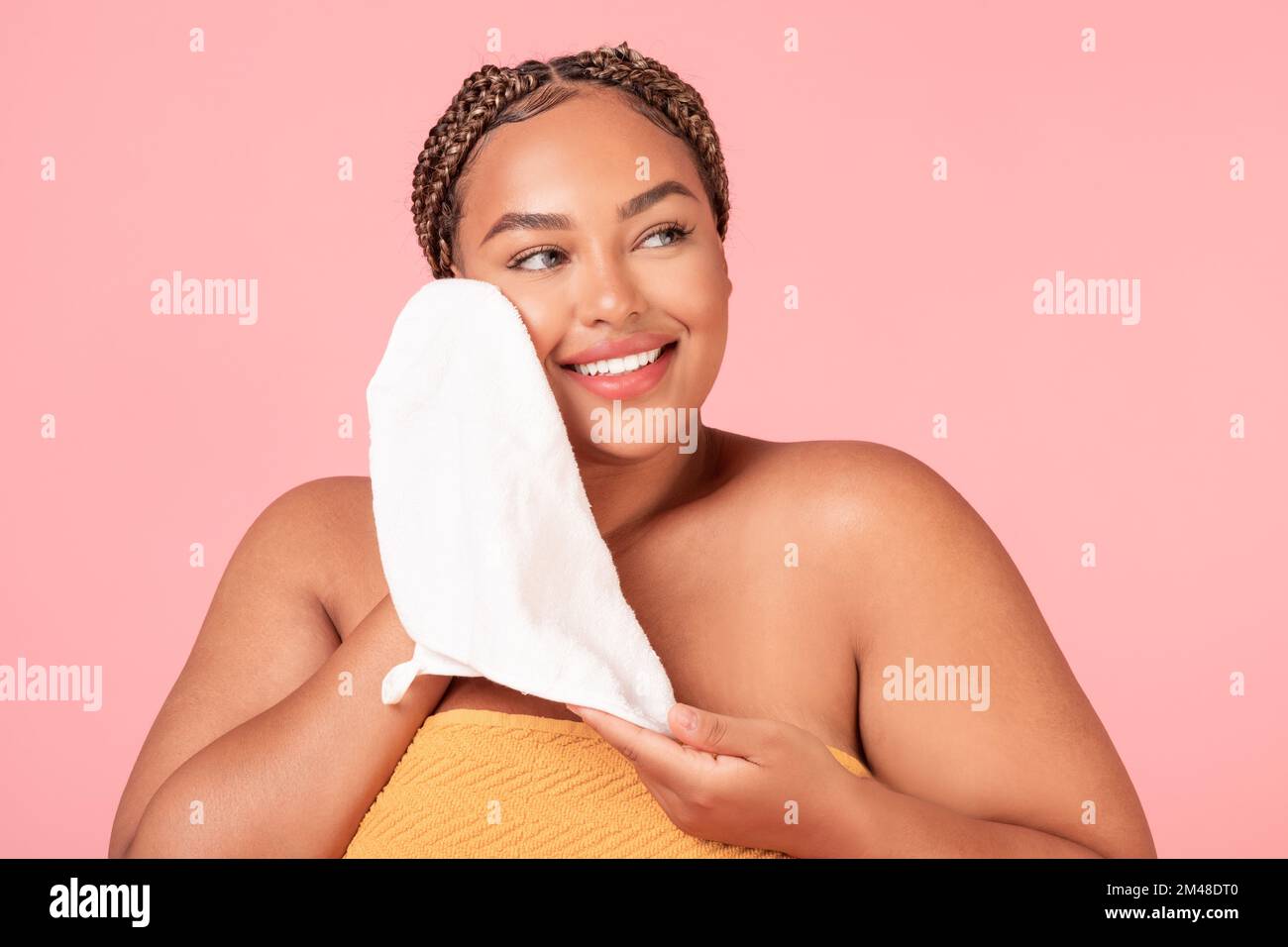 Happy black oversize lady drying clean face with soft white towel ...