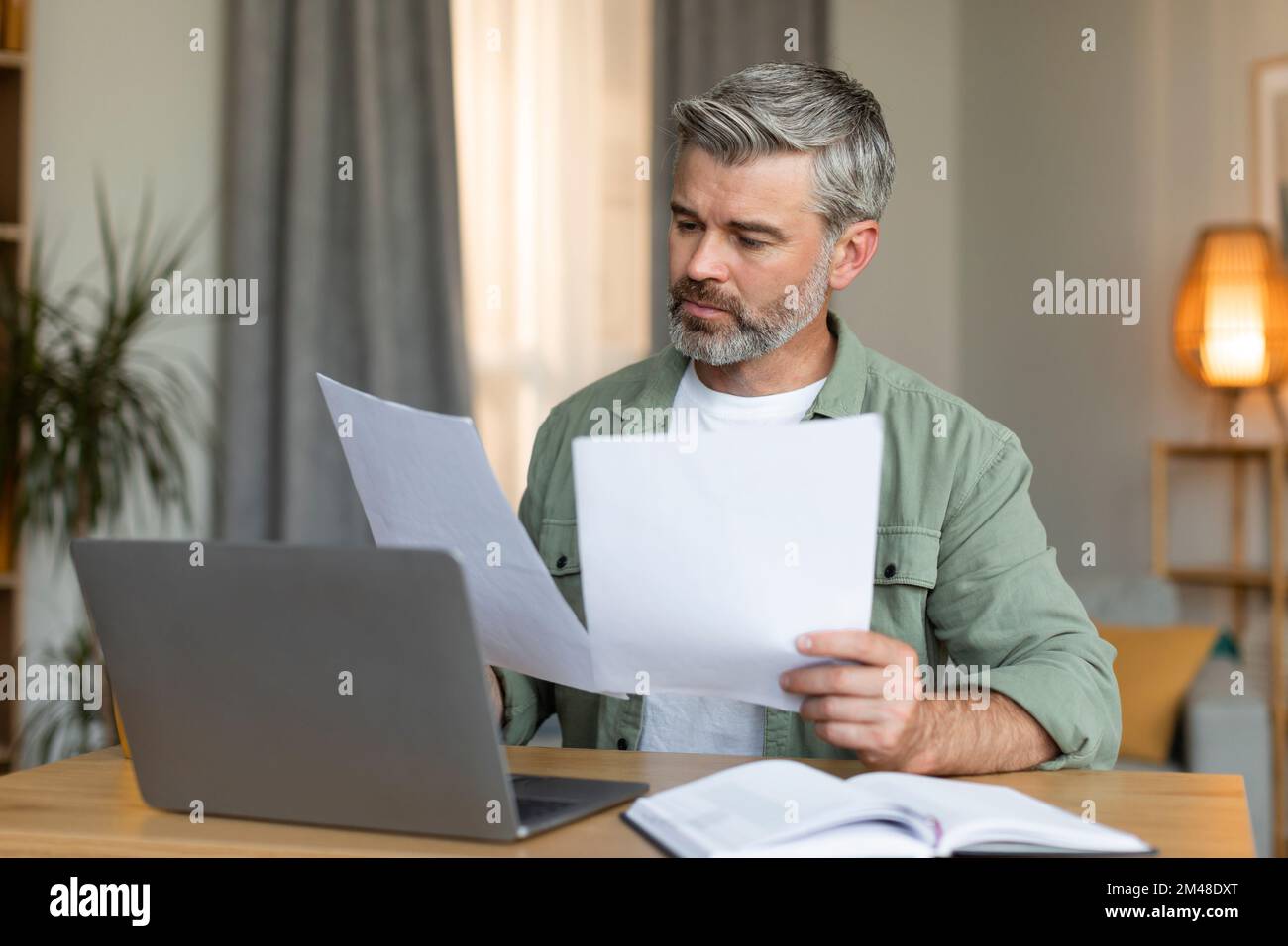 Serious busy old caucasian man manager works with documents, sits at ...