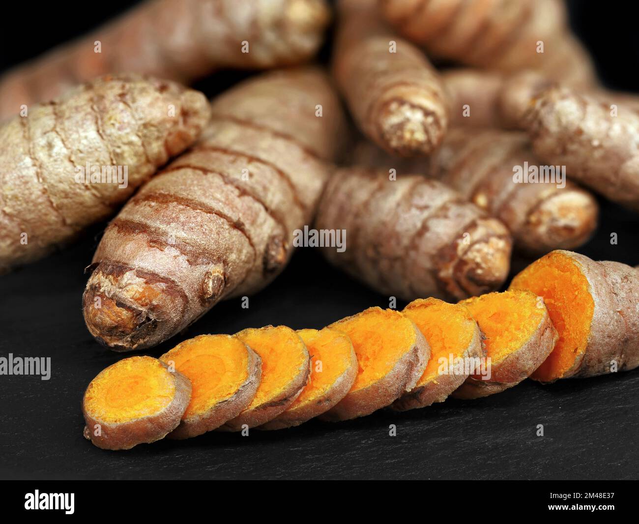 close up of sliced turmeric roots, Curcuma longa on black slate board ...