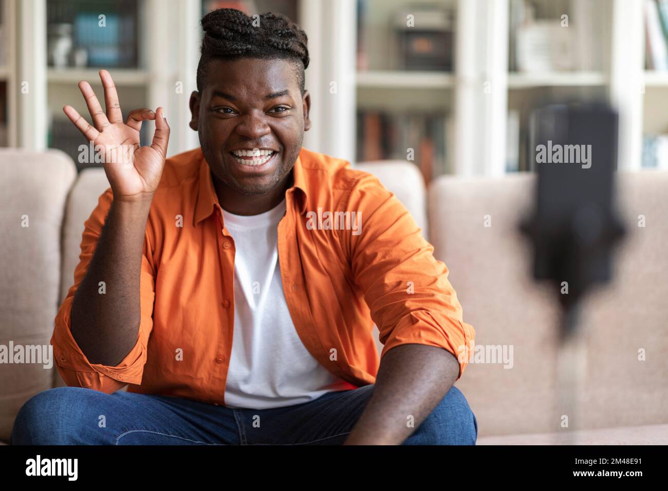 Positive cool black guy vlogger streaming from home, using phone Stock ...