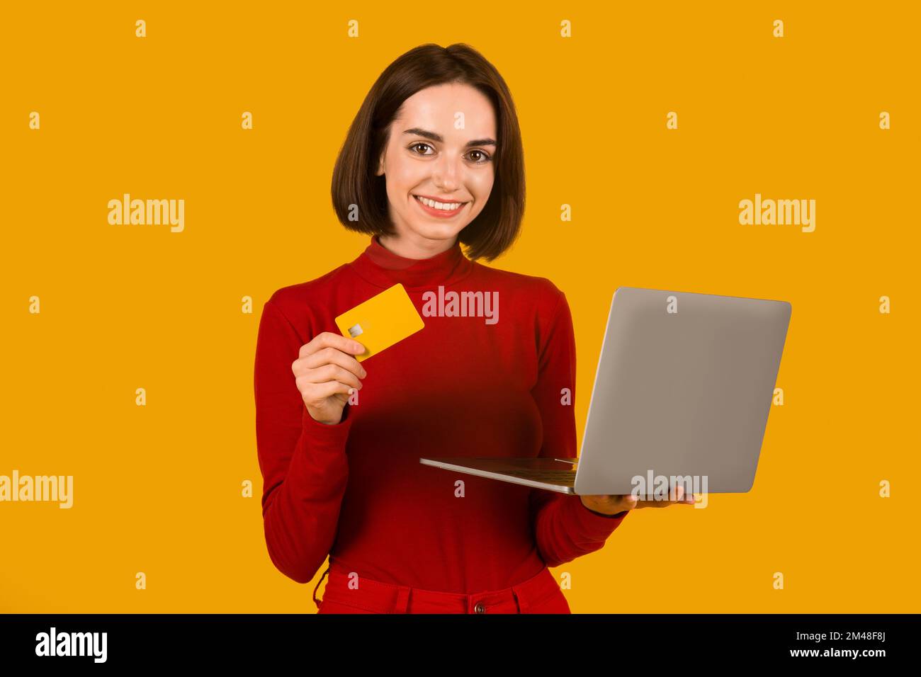 Smiling young lady banking online, holding laptop and credit card Stock ...