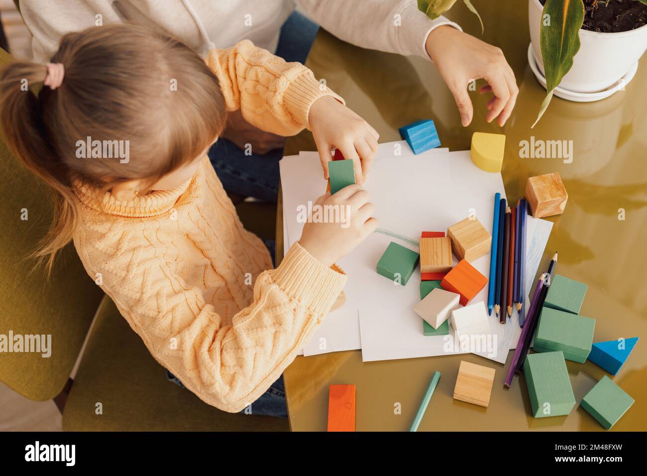 Mom is playing with her daughter. Mom and little girl built a tower of ...