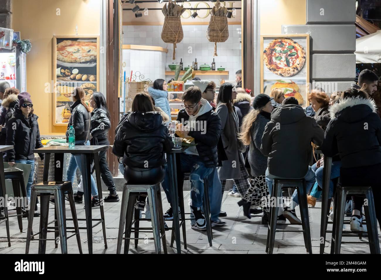 Naples, Italy - December 11, 2022: Group of people buy and eat food in ...
