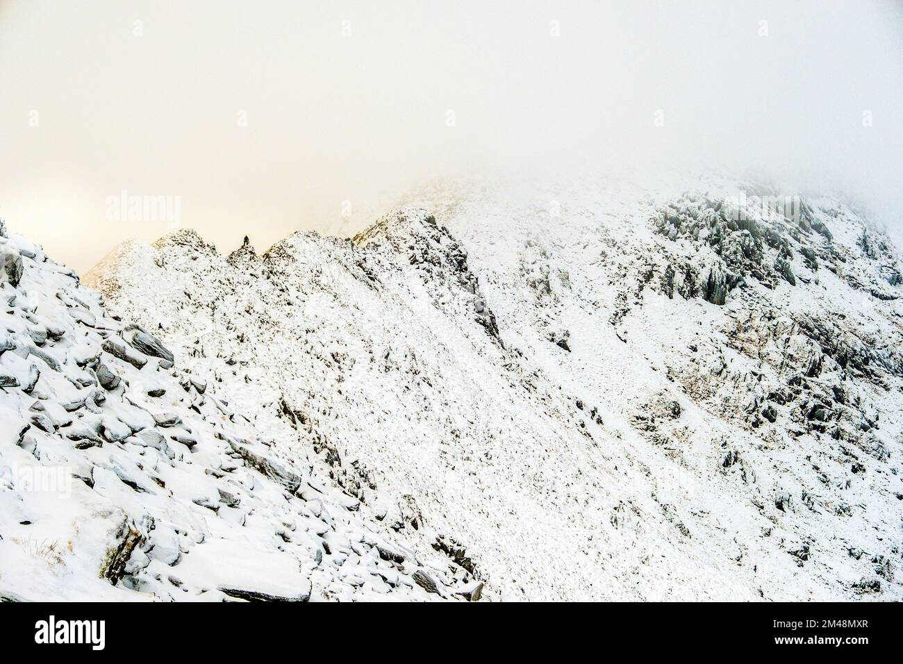 Mountaineers on a winter traverse of Striding Edge on Helvellyn in the ...