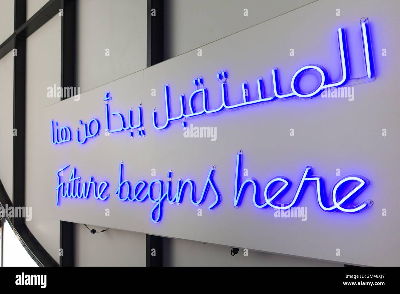 Blue neon signs FUTURE BEGINS HERE in English and Arabic on wall . High ...