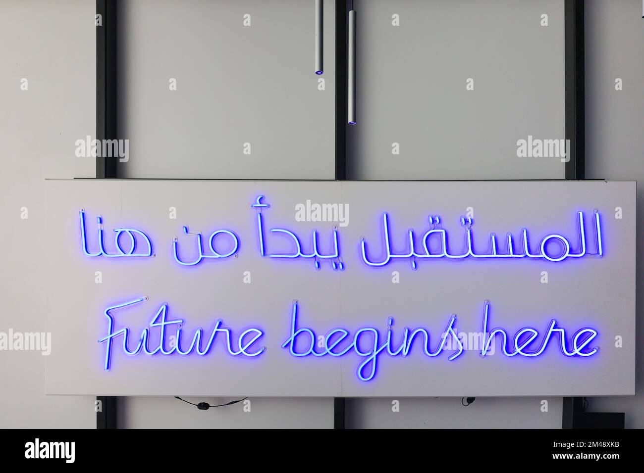 Blue neon signs FUTURE BEGINS HERE in English and Arabic on wall . High ...