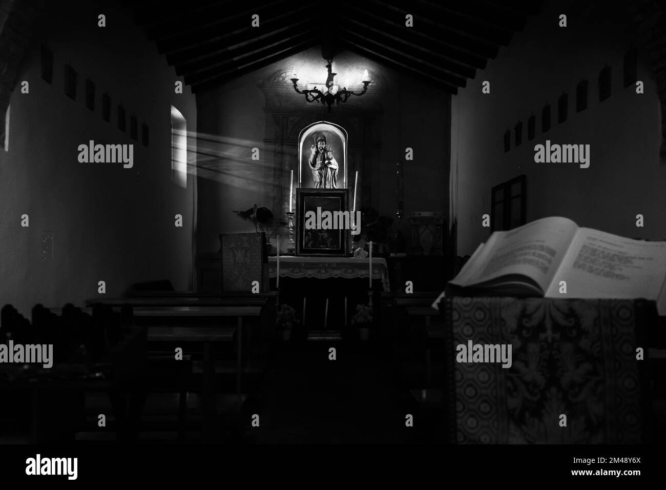A grayscale inside a church building with an opened book in front and ...
